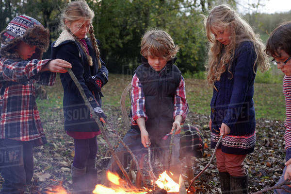 Children poking bonfire outdoors - Royalty-free Stock Photo | Dissolve