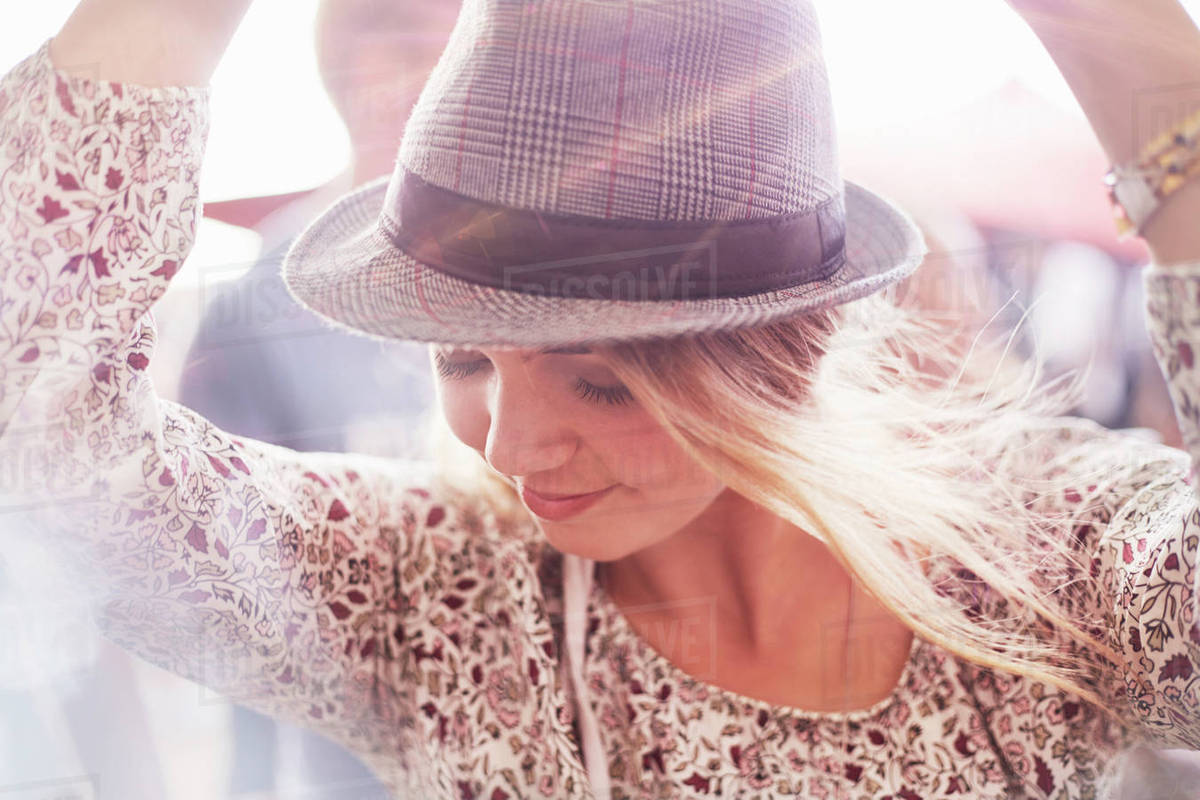 Close up young blonde woman with fedora dancing at music festival ...