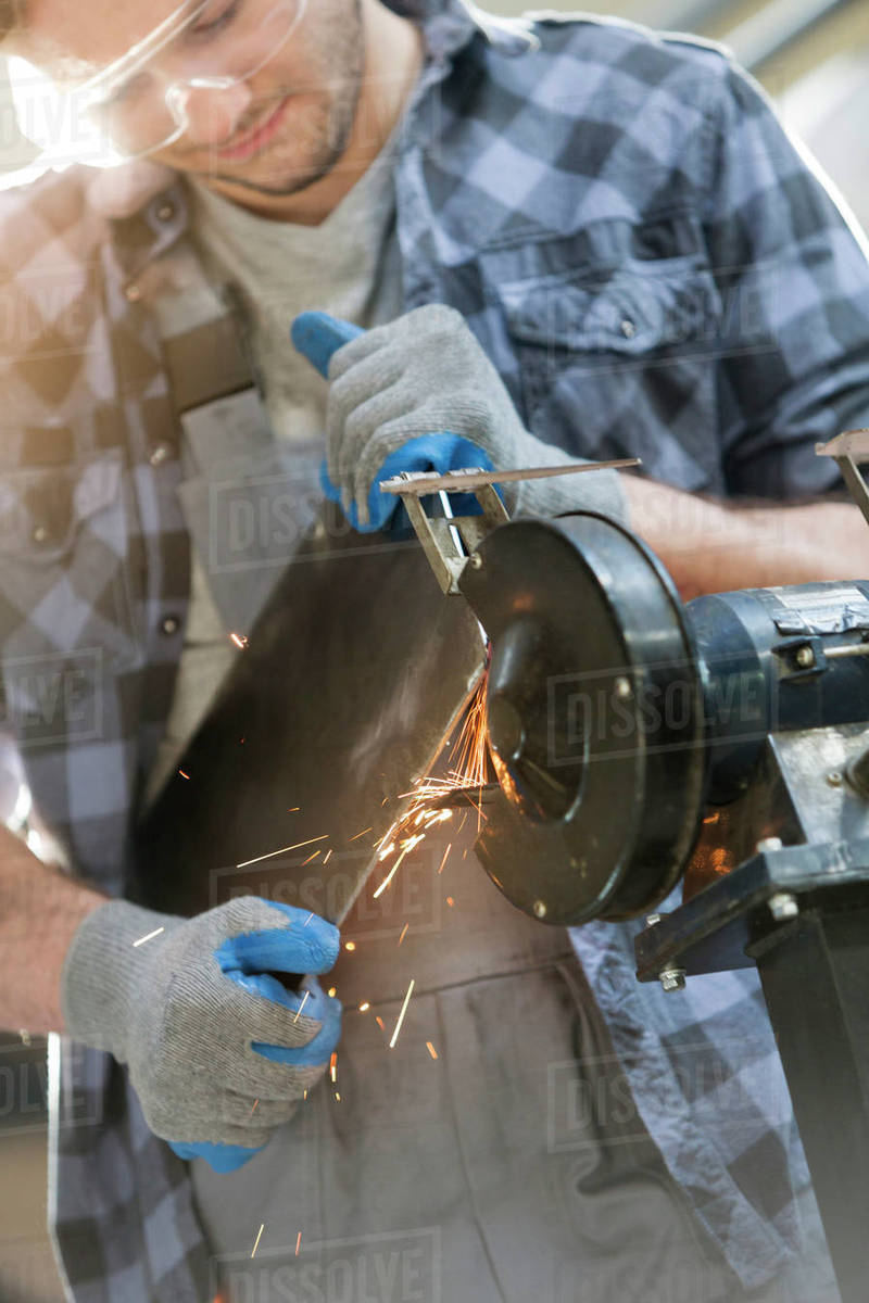Metal worker using sander in workshop - Royalty-free Stock Photo | Dissolve