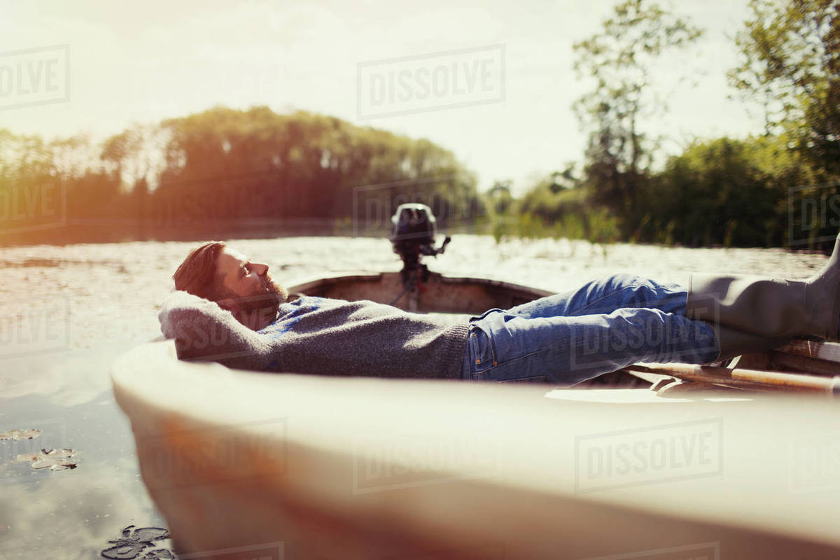 Serene man laying relaxing in canoe on sunny lake - Royalty-free Stock ...