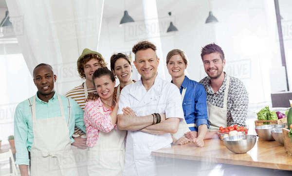 Portrait smiling chef teacher and students in cooking class kitchen ...