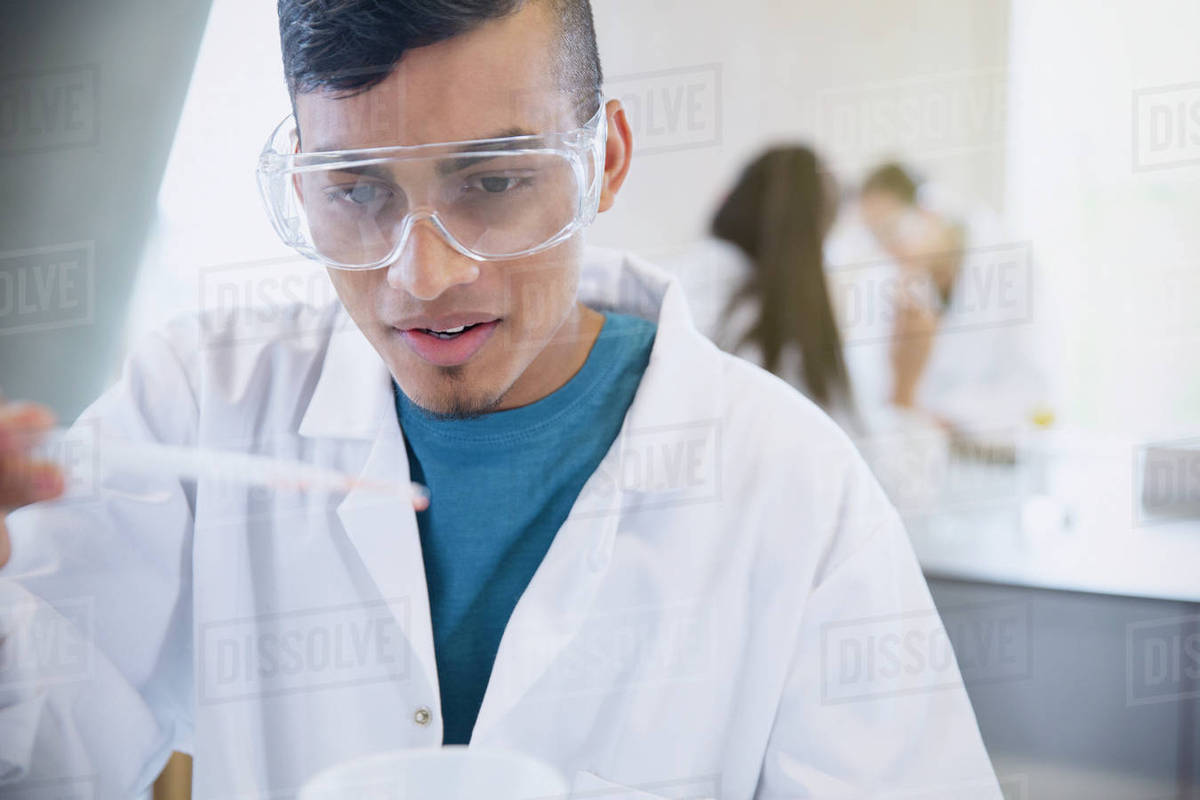 Male college student conducting scientific experiment in science ...