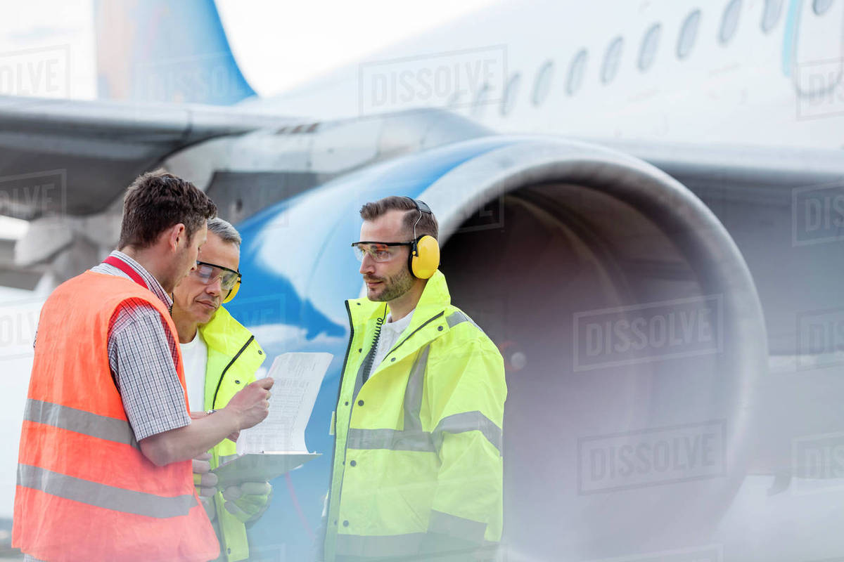 Air traffic control ground crew with clipboard next to airplane on ...