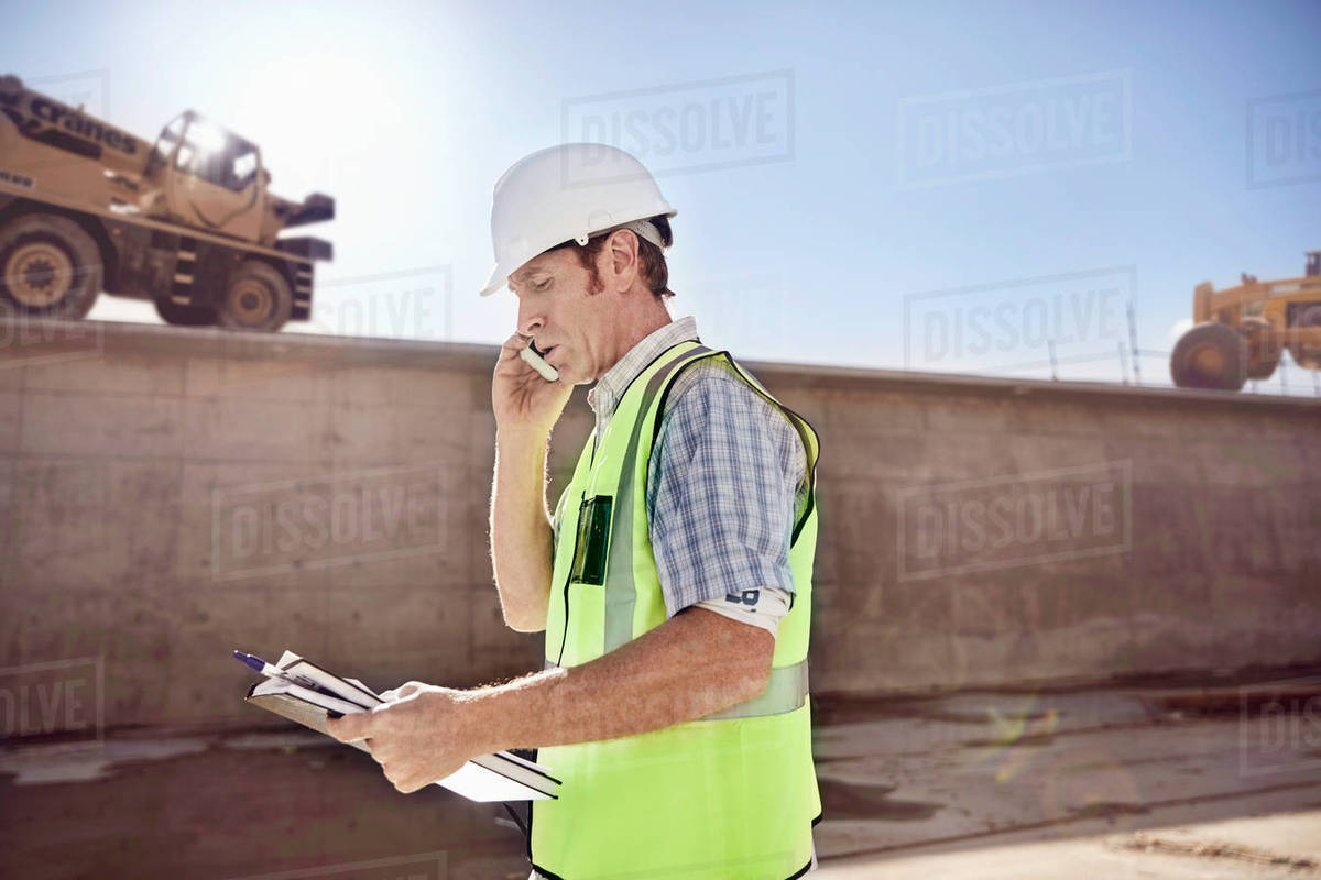 Construction worker foreman talking on cell phone at sunny construction ...