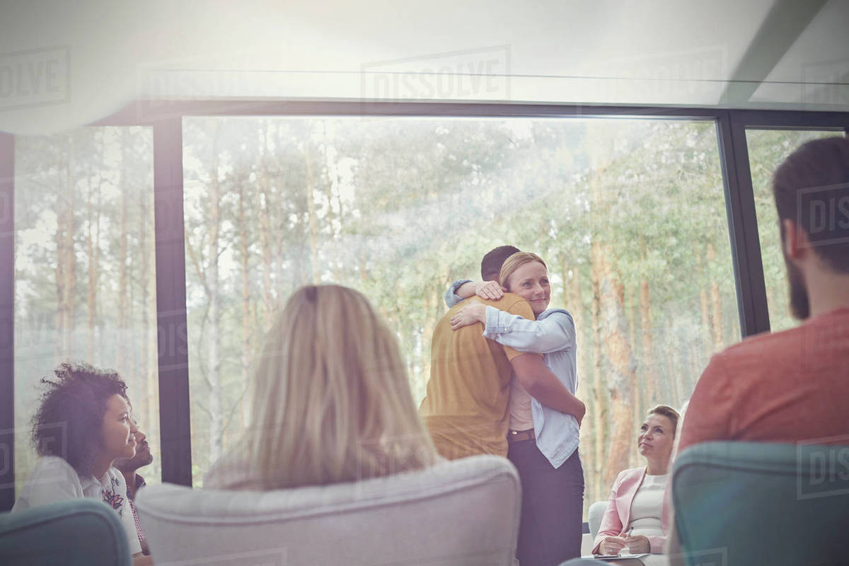 Man and woman hugging in group therapy session - Stock Photo - Dissolve