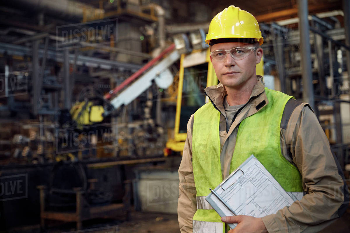 Portrait serious, confident steelworker with clipboard in steel mill ...