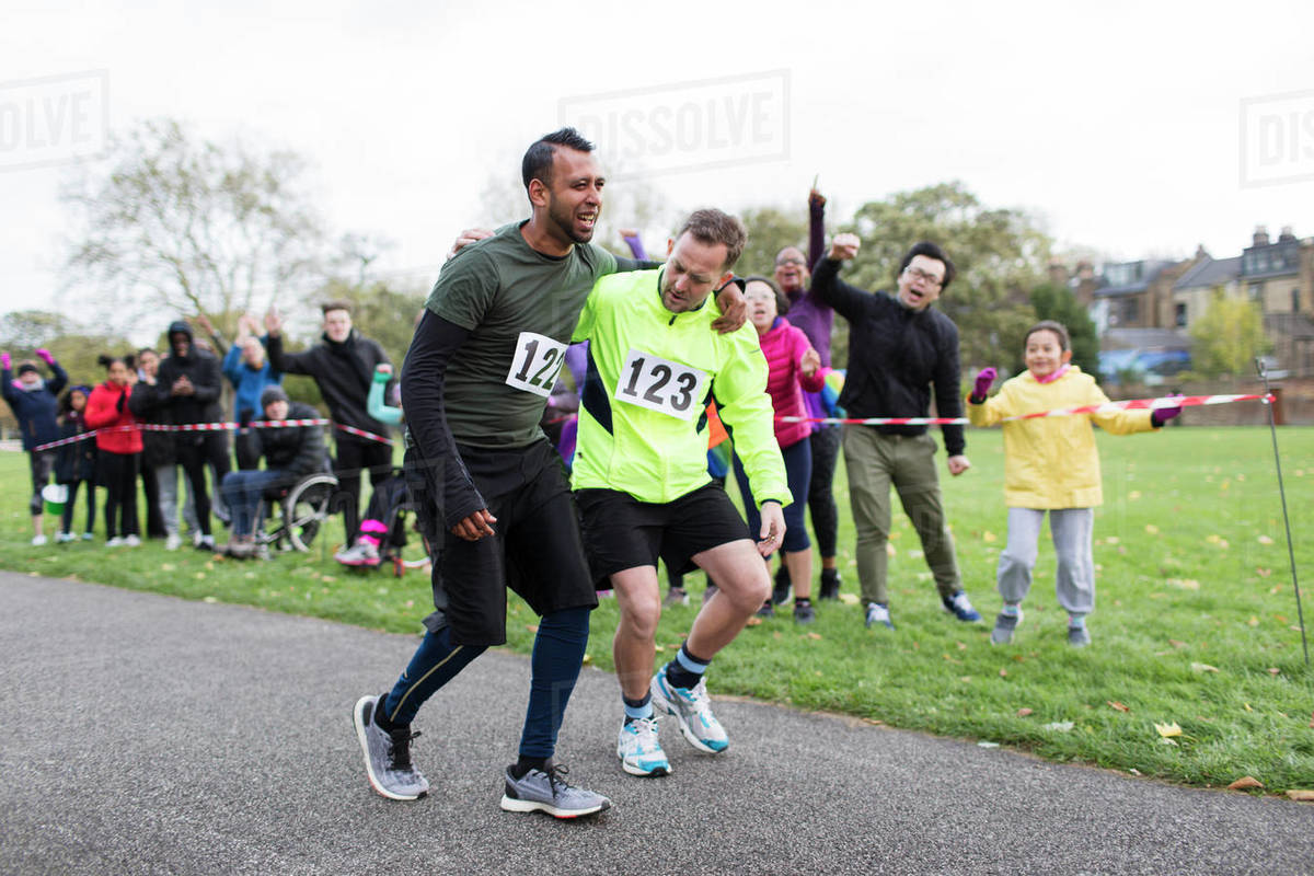 Spectators cheering for man helping injured marathon runner - Stock ...