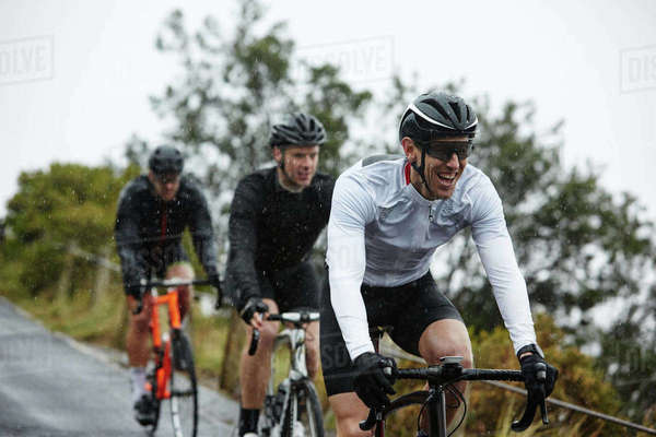 Smiling male cyclist cycling with friends - Stock Photo - Dissolve