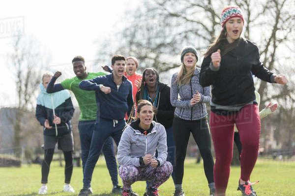 Team cheering woman running in sunny park - Stock Photo - Dissolve