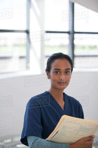 Nurse carrying folder in hospital hallway - Stock Photo - Dissolve