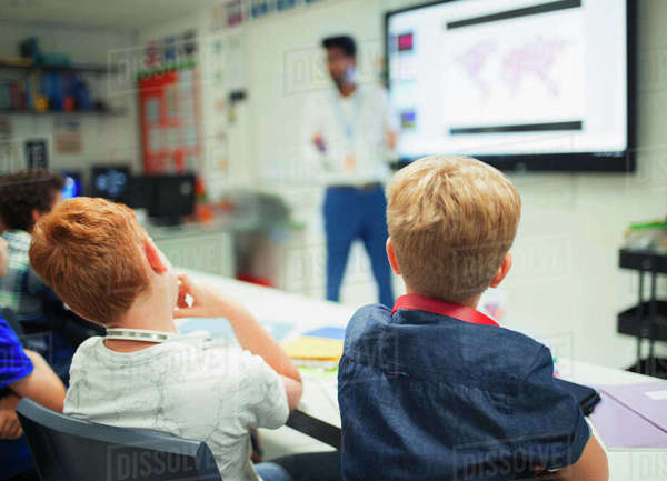 Junior high school boys watching teacher during lesson in classroom ...