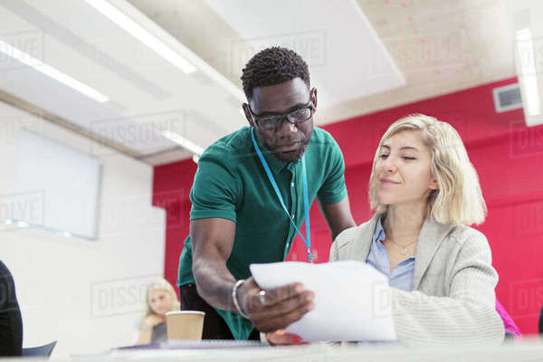 Community college instructor helping student with paperwork in ...