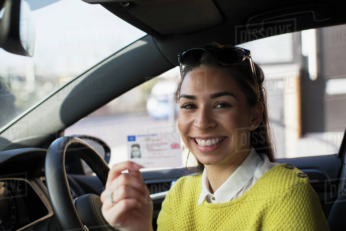 Portrait happy young woman holding new drivers license in car - Royalty ...