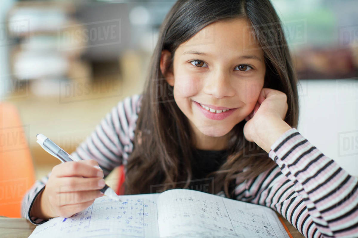 Portrait smiling, confident girl doing homework - Stock Photo - Dissolve