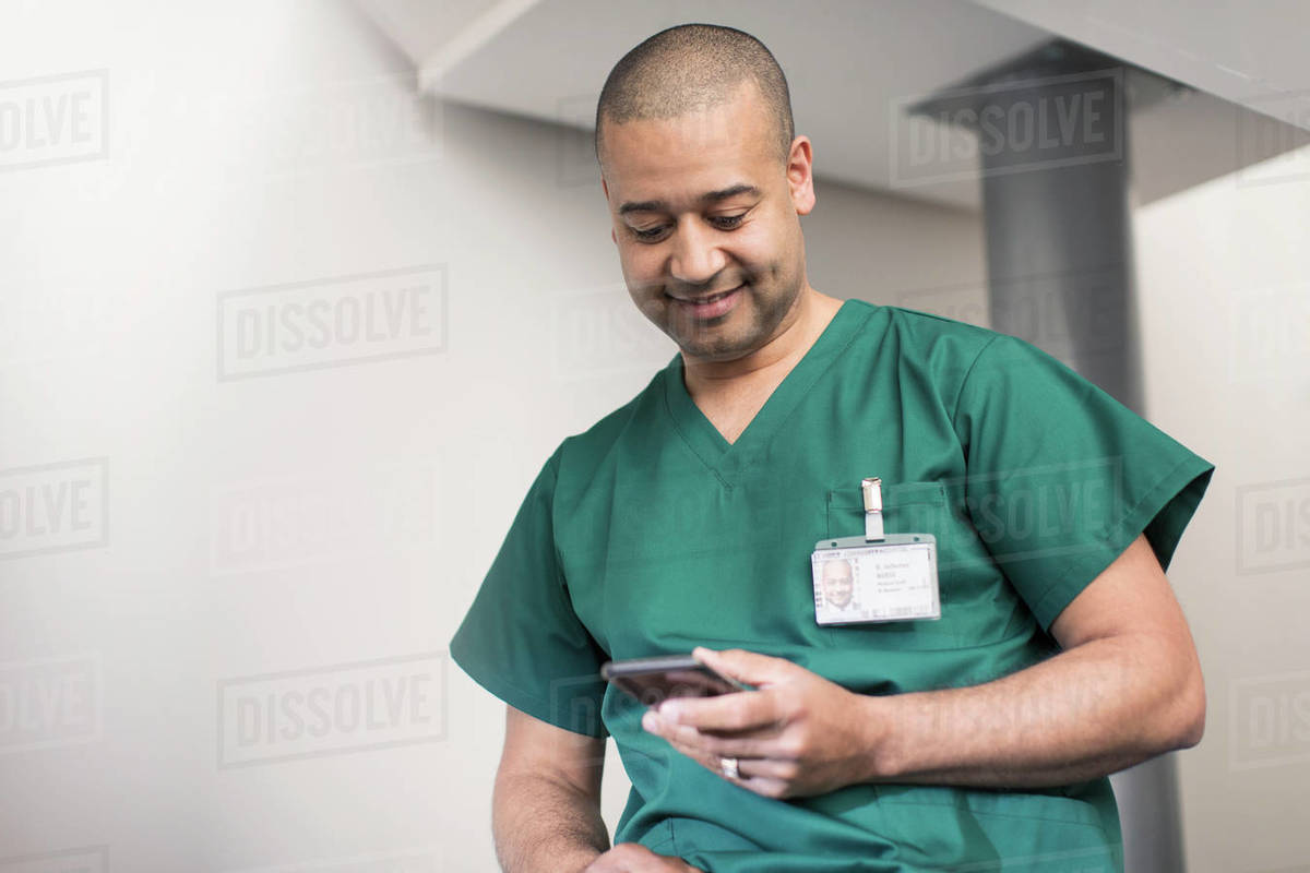 Male surgeon using smart phone - Stock Photo - Dissolve