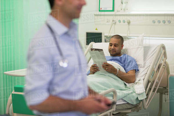 Male patient reading newspaper, resting in hospital room - Royalty-free ...
