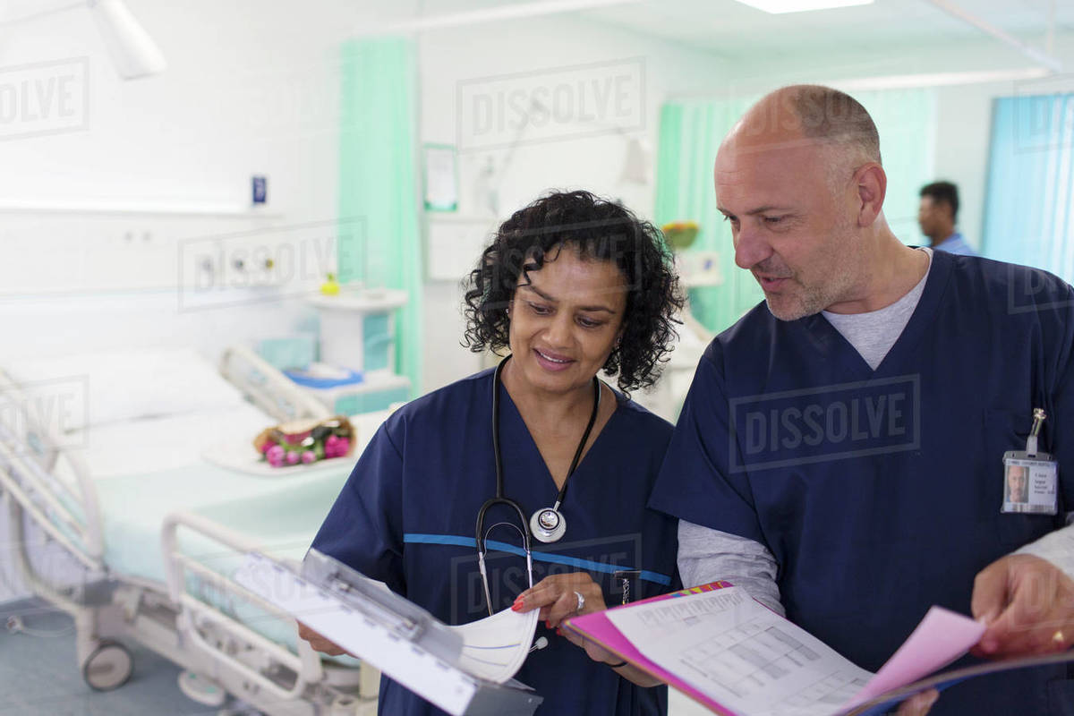 Doctors with medical charts making rounds, consulting in hospital ward ...