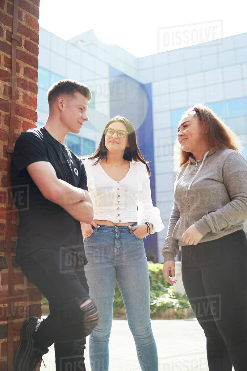 College students talking outside sunny building - Stock Photo - Dissolve