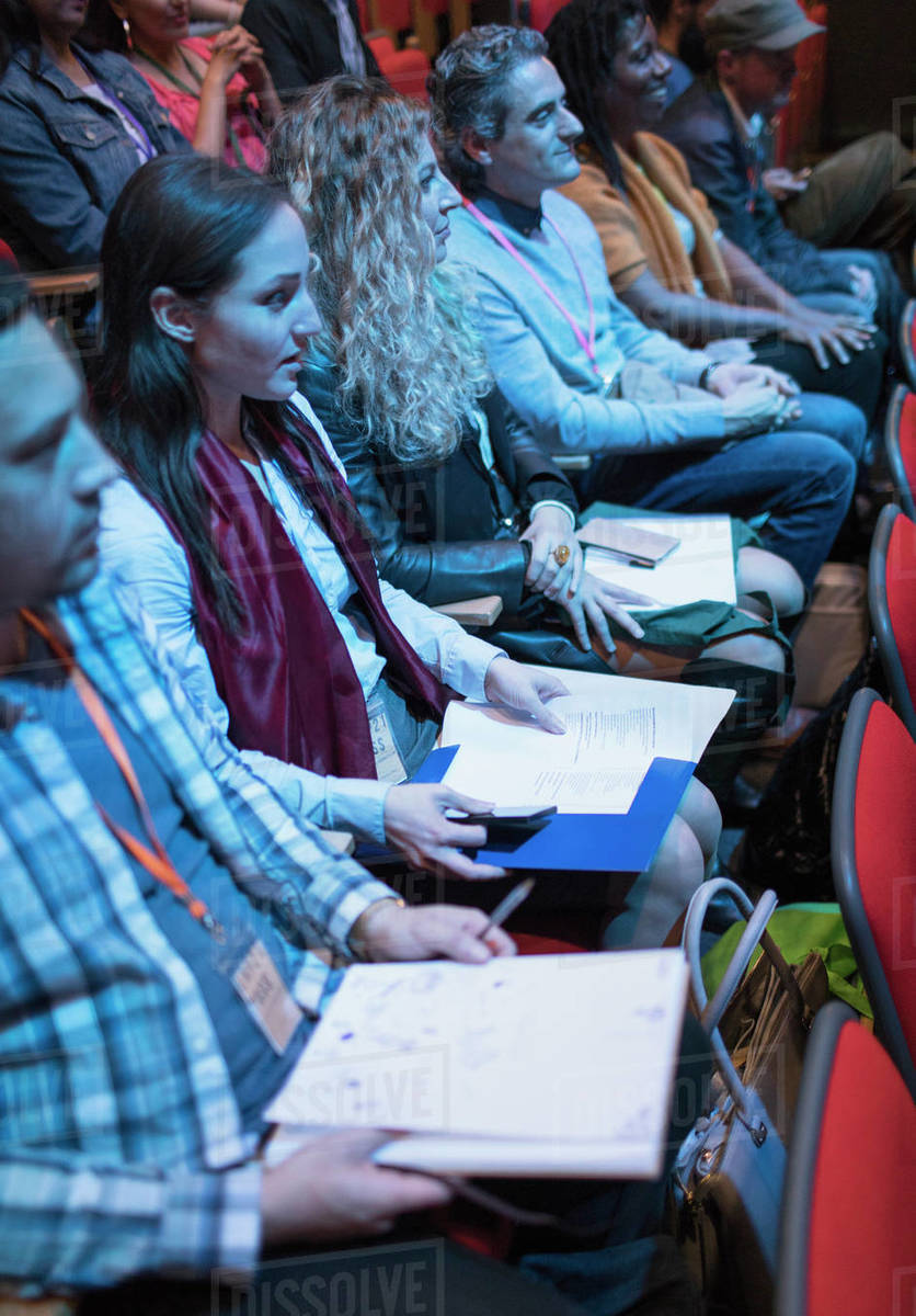 Attentive conference audience with paperwork - Stock Photo - Dissolve