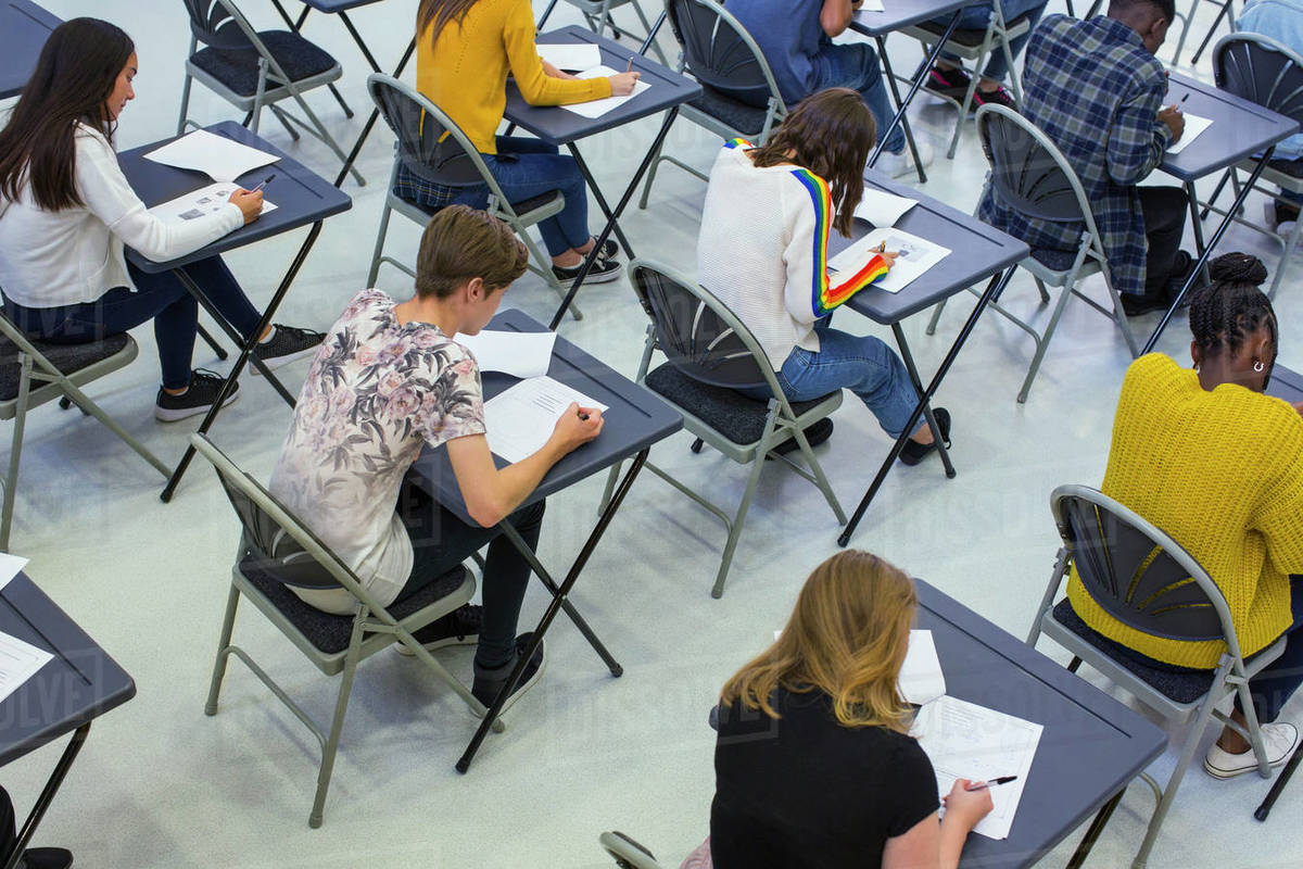 High school students taking exam at desks in classroom - Royalty-free ...