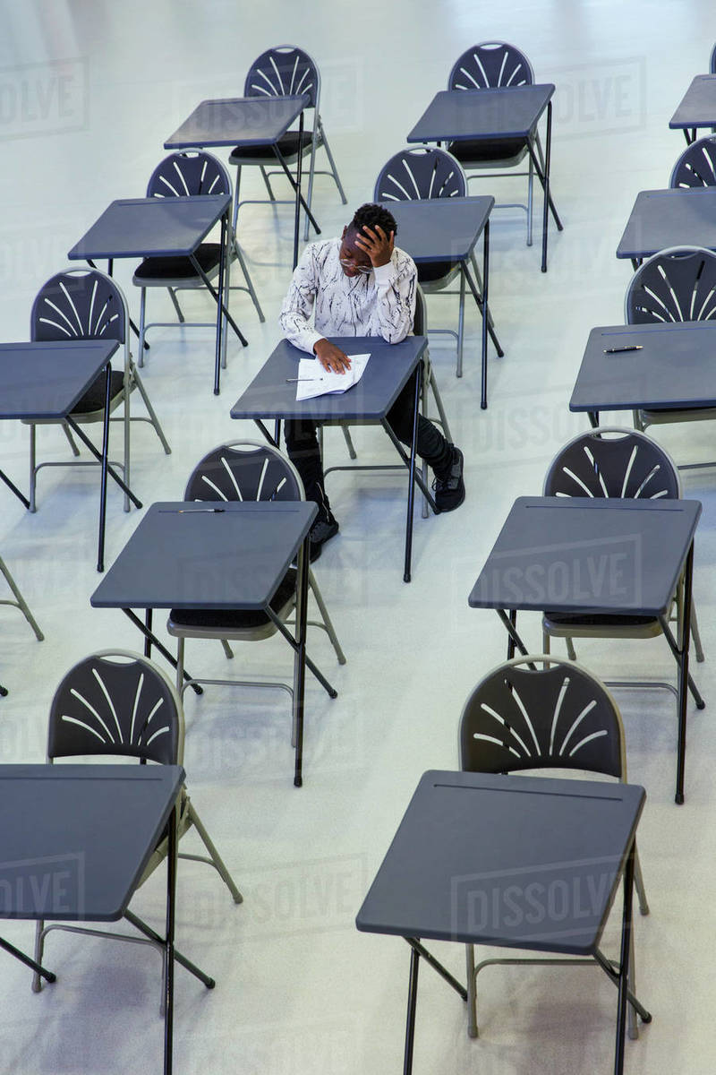Dedicated high school boy student taking exam at desk in classroom ...