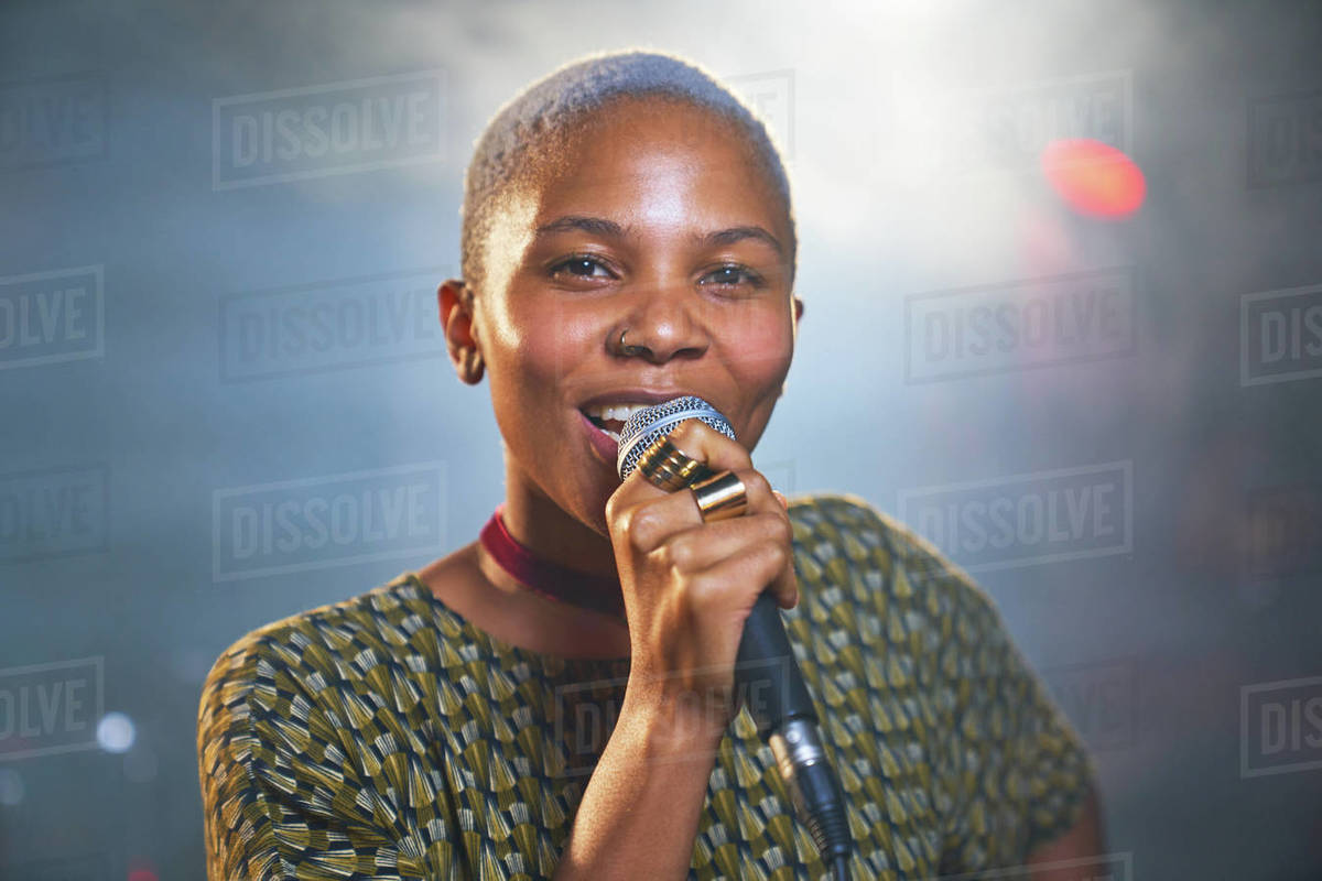 Portrait happy young female musician singing into microphone - Stock ...