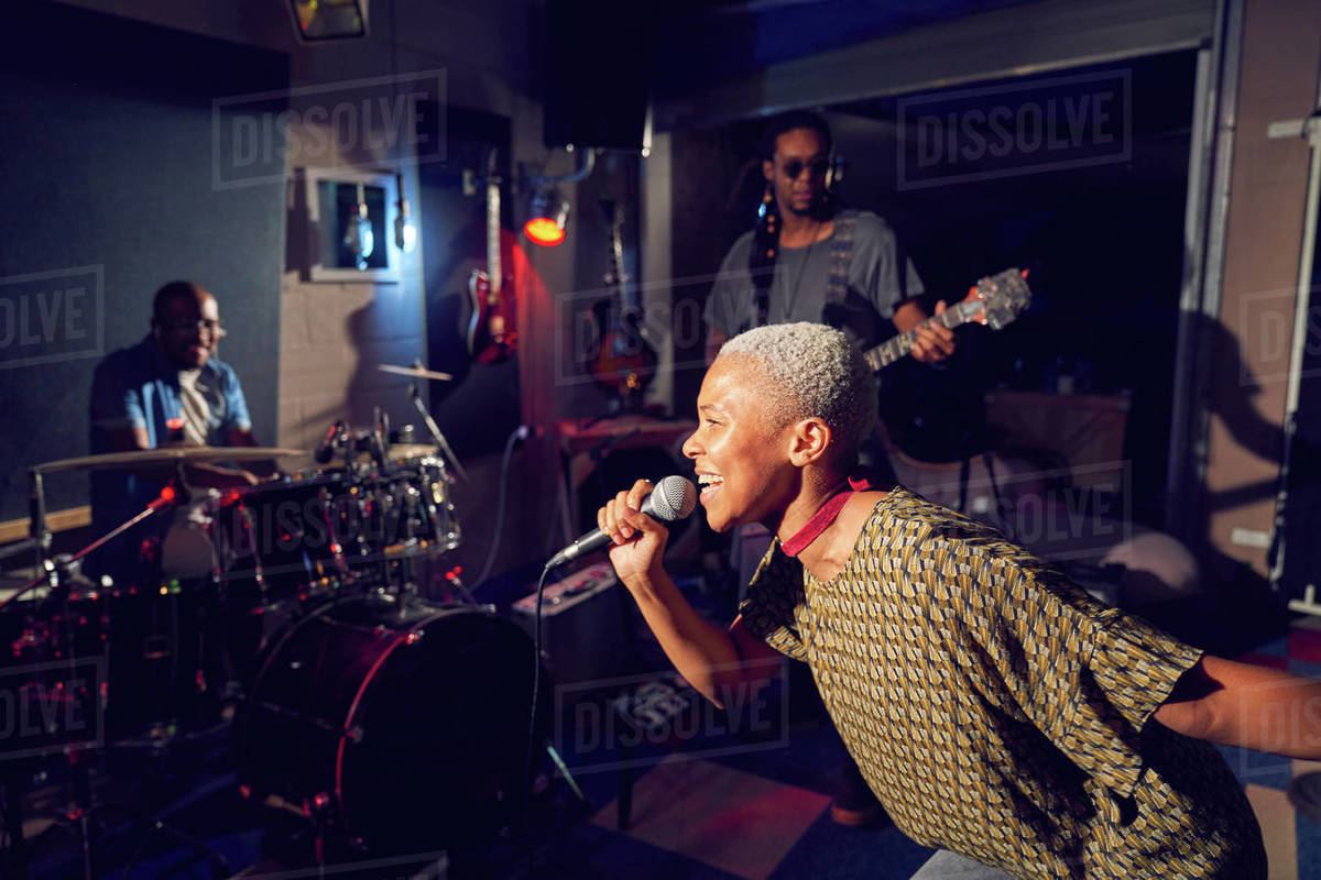 Female musician singing into microphone in recording studio - Stock ...