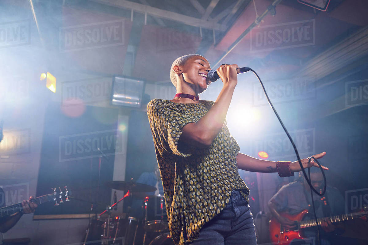 Female musician singing into microphone in recording studio - Stock ...