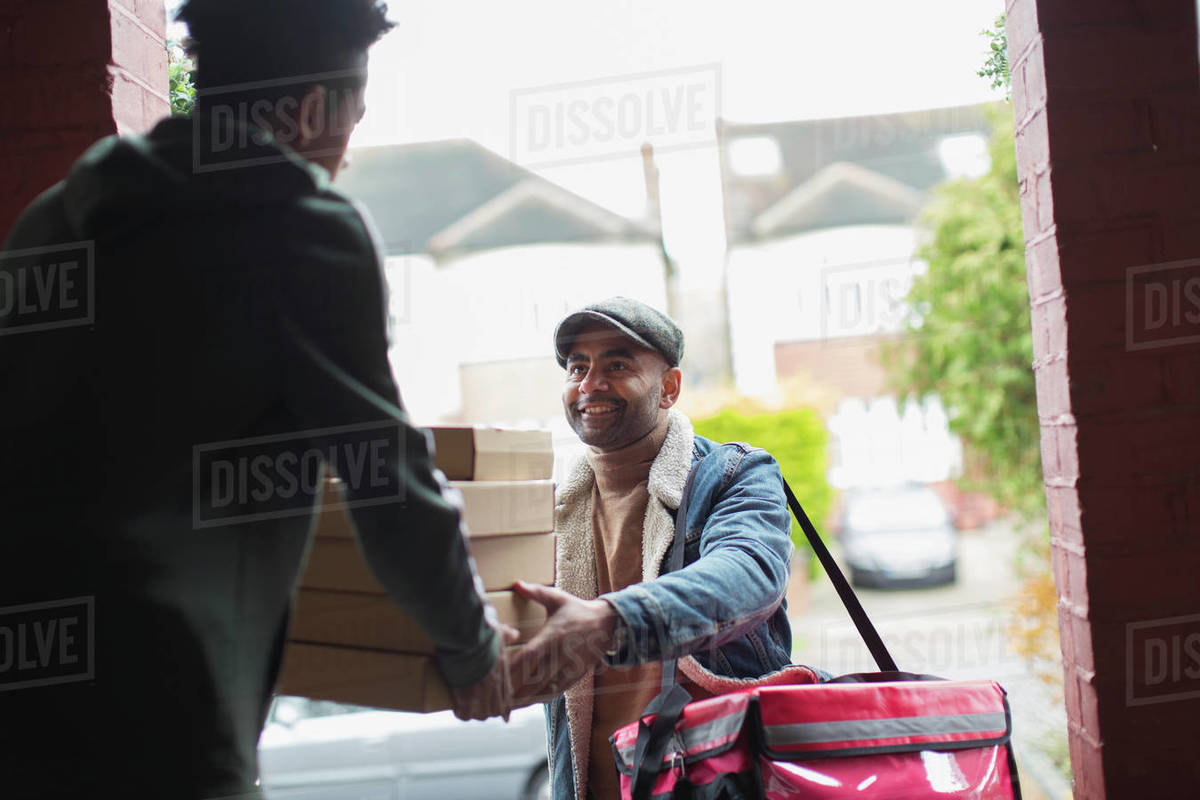 Friendly food delivery man with boxes at front door - Stock Photo ...