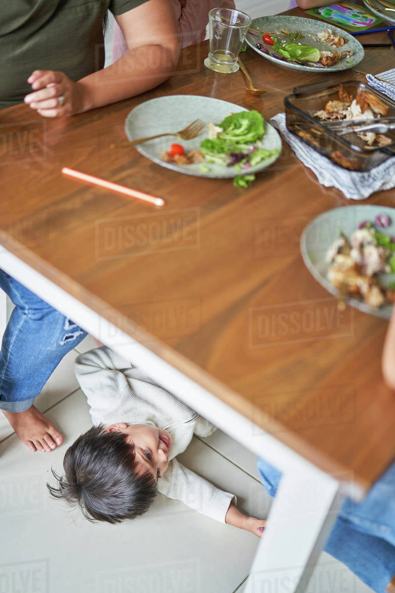 Boy playing under dinner table - Royalty-free Stock Photo | Dissolve
