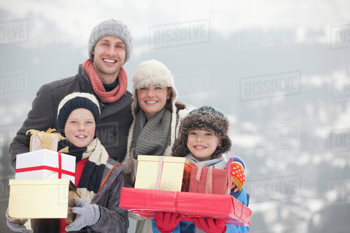Portrait of happy family with Christmas gifts in snow - Royalty-free ...