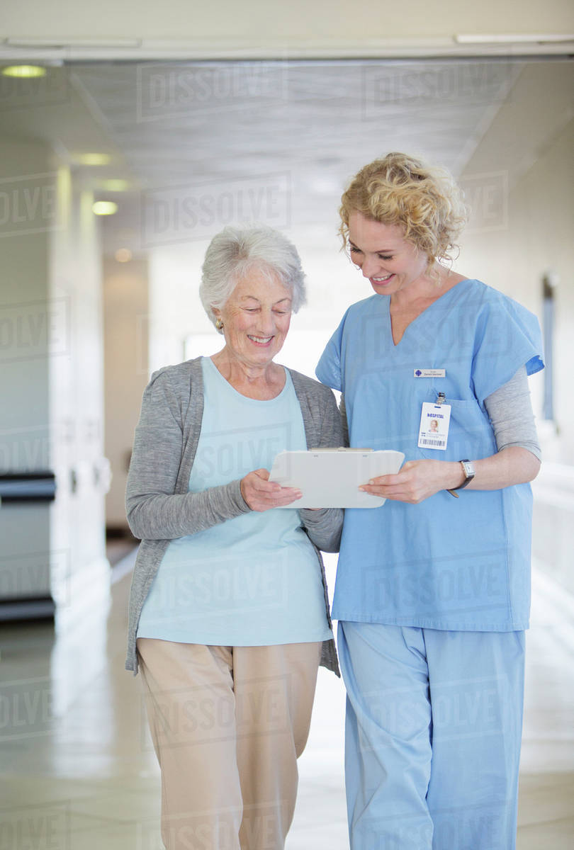 Nurse and aging patient reading chart in hospital corridor - Royalty ...