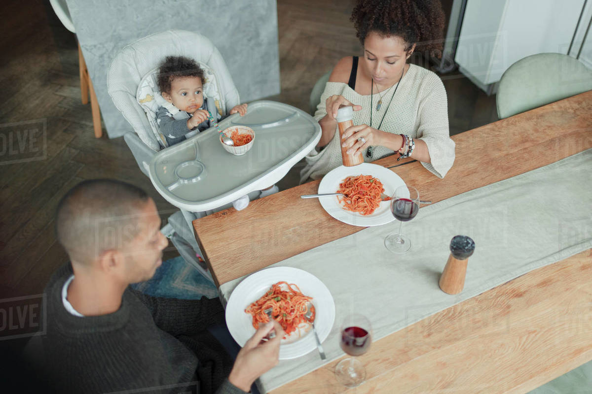 Family eating spaghetti at dining table and high chair - Royalty-free ...