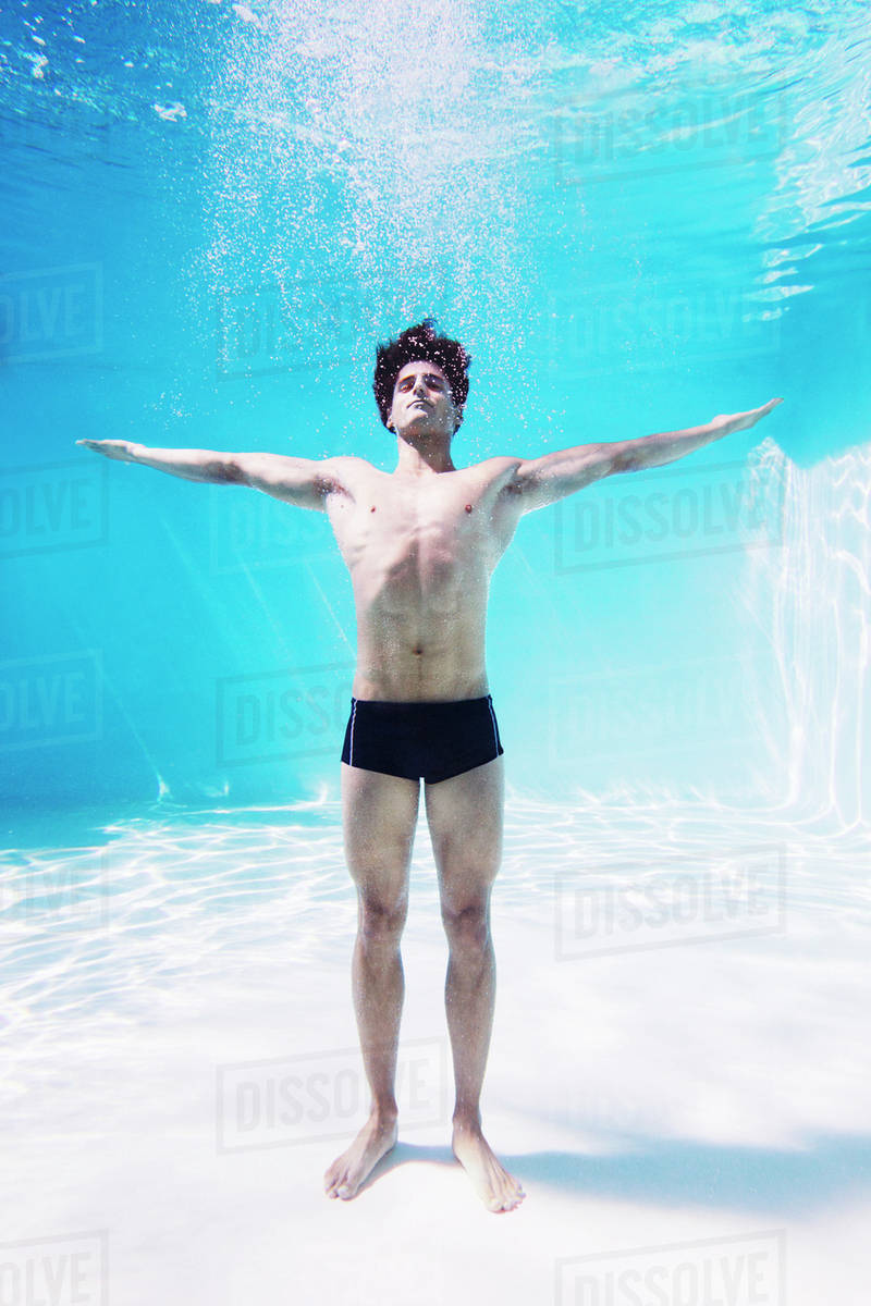 Man standing underwater in swimming pool with arms outstretched ...