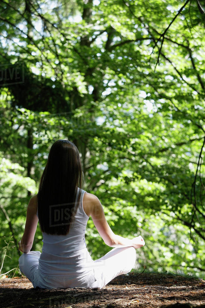 Back view of young woman meditating in forest - Royalty-free Stock ...