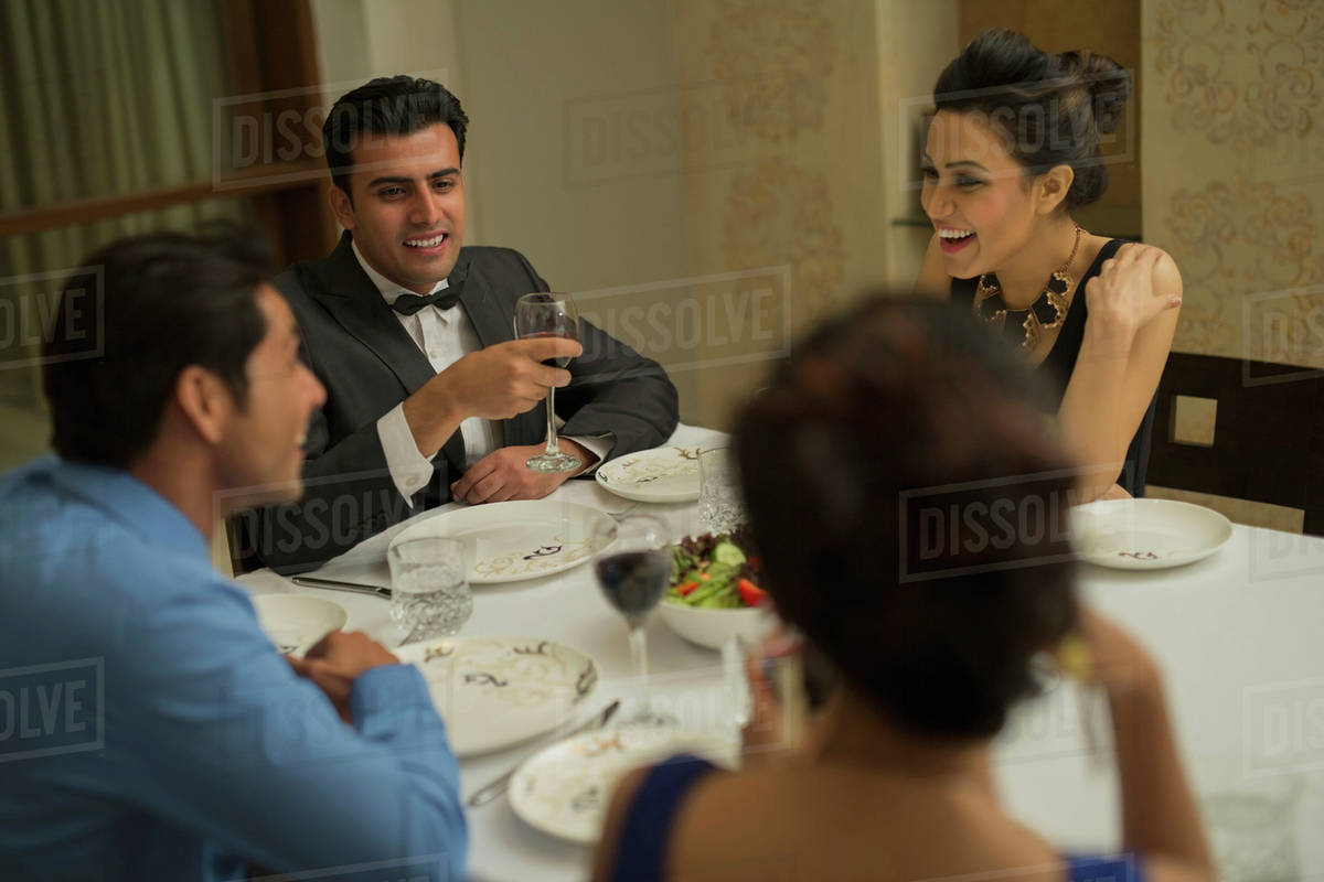 Four friends at dinner laughing - Stock Photo - Dissolve
