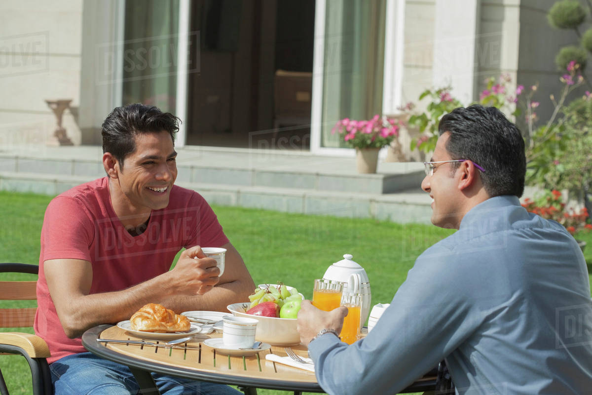 Two men eating breakfast in garden - Royalty-free Stock Photo | Dissolve