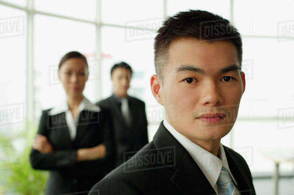Businessman looking at camera, people in the background - Stock Photo ...