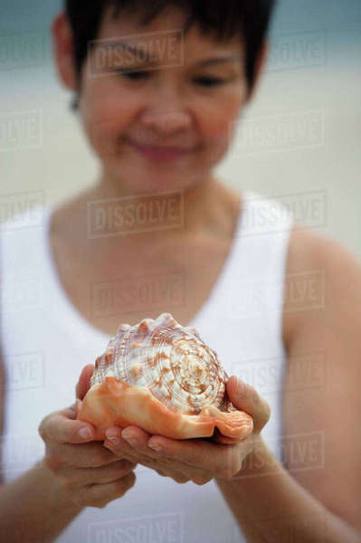 Woman at the beach holding a sea shell - Royalty-free Stock Photo ...