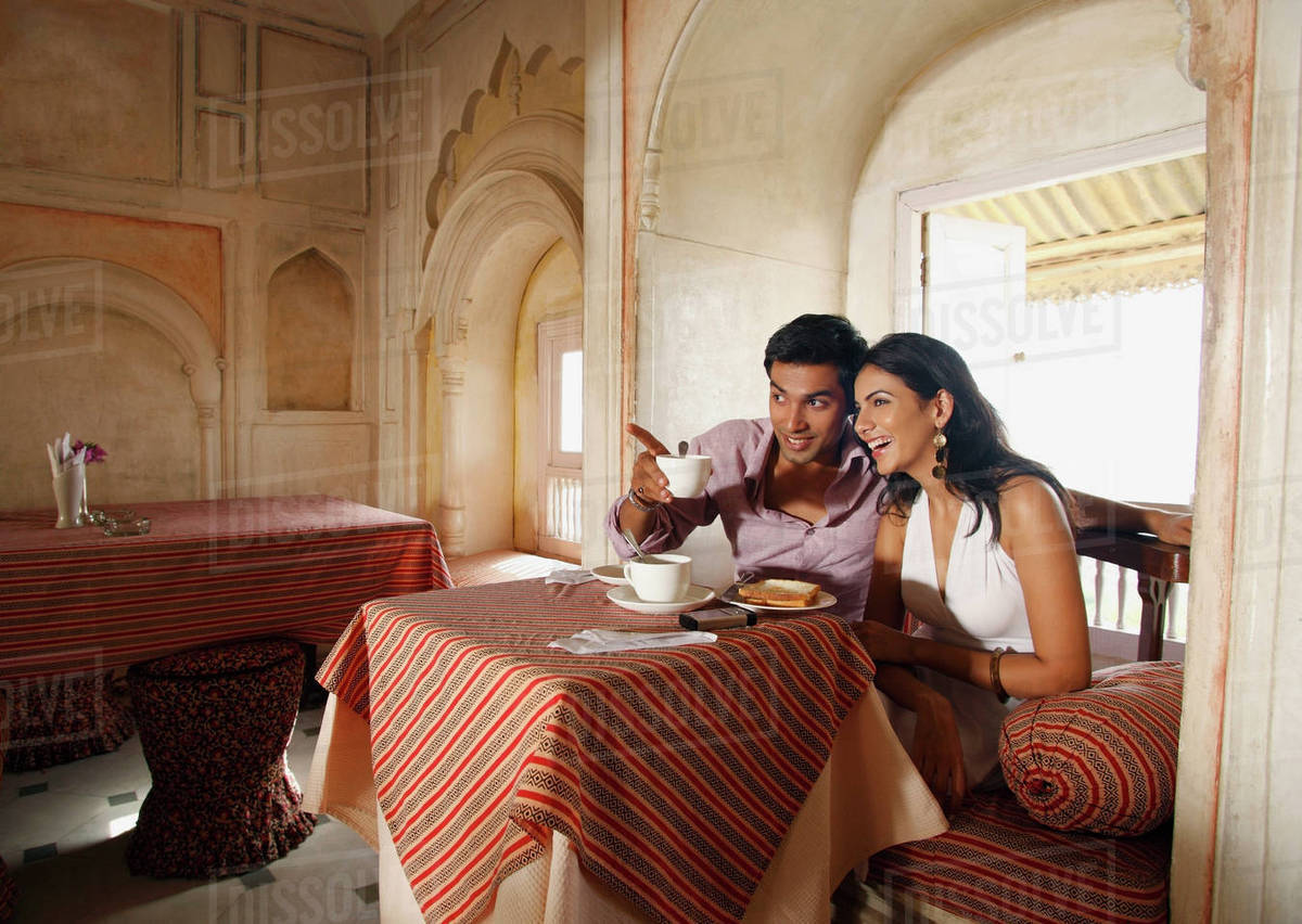 Couple sitting at table, man pointing out - Royalty-free Stock Photo ...