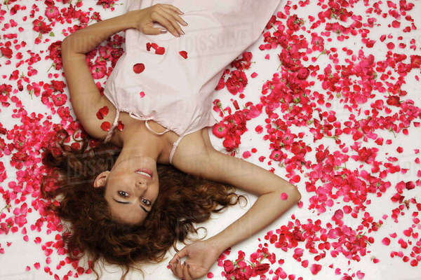 Woman lying surrounded by rose petals - Stock Photo - Dissolve