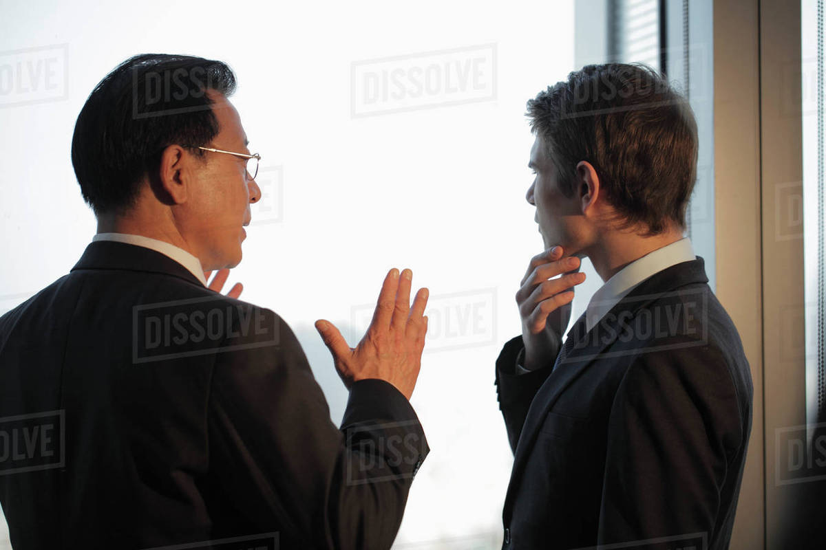 Two men talking in front of window - Royalty-free Stock Photo | Dissolve