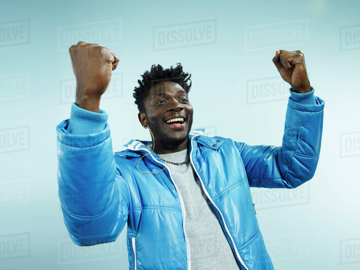 A young hip man with his arms raised in celebration - Stock Photo ...