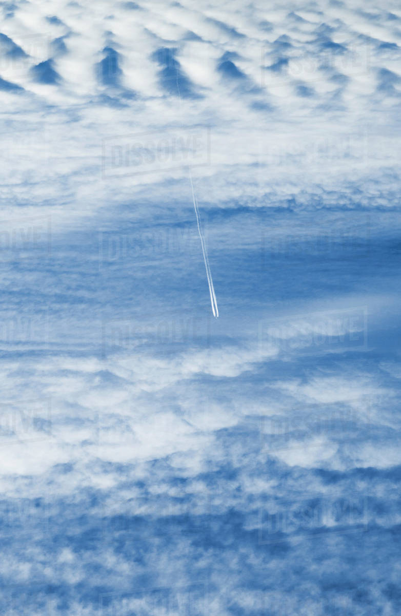 Plane vapor trail over cloudscape - Royalty-free Stock Photo | Dissolve