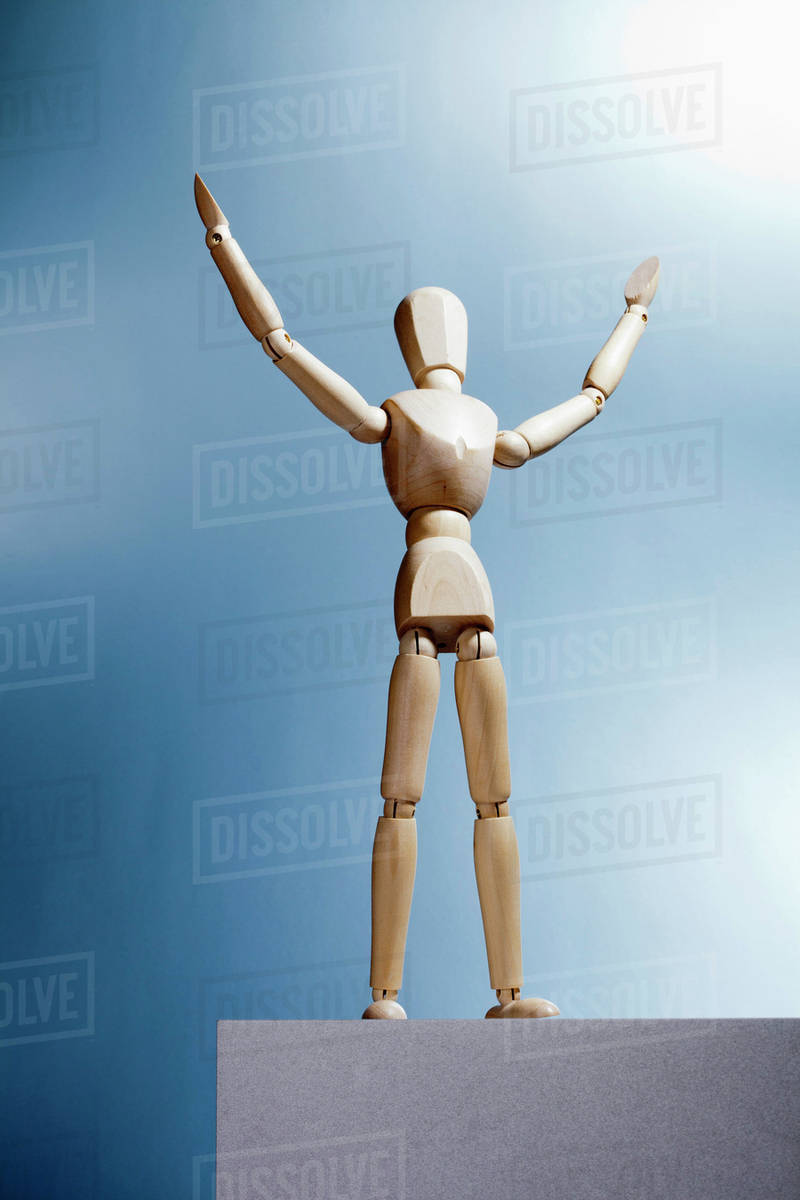 An artist's figure standing atop a box with arms raised and head tilted ...