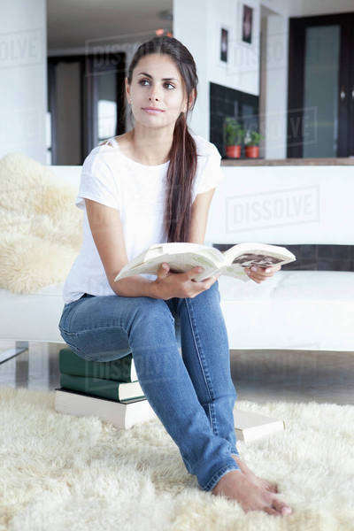 Woman sitting on books and reading - Royalty-free Stock Photo | Dissolve