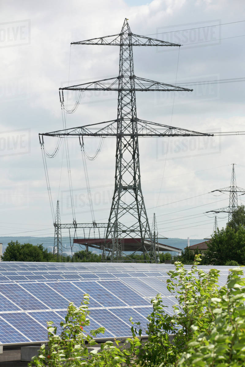 Solar panels in front of an electricity pylon - Stock Photo - Dissolve