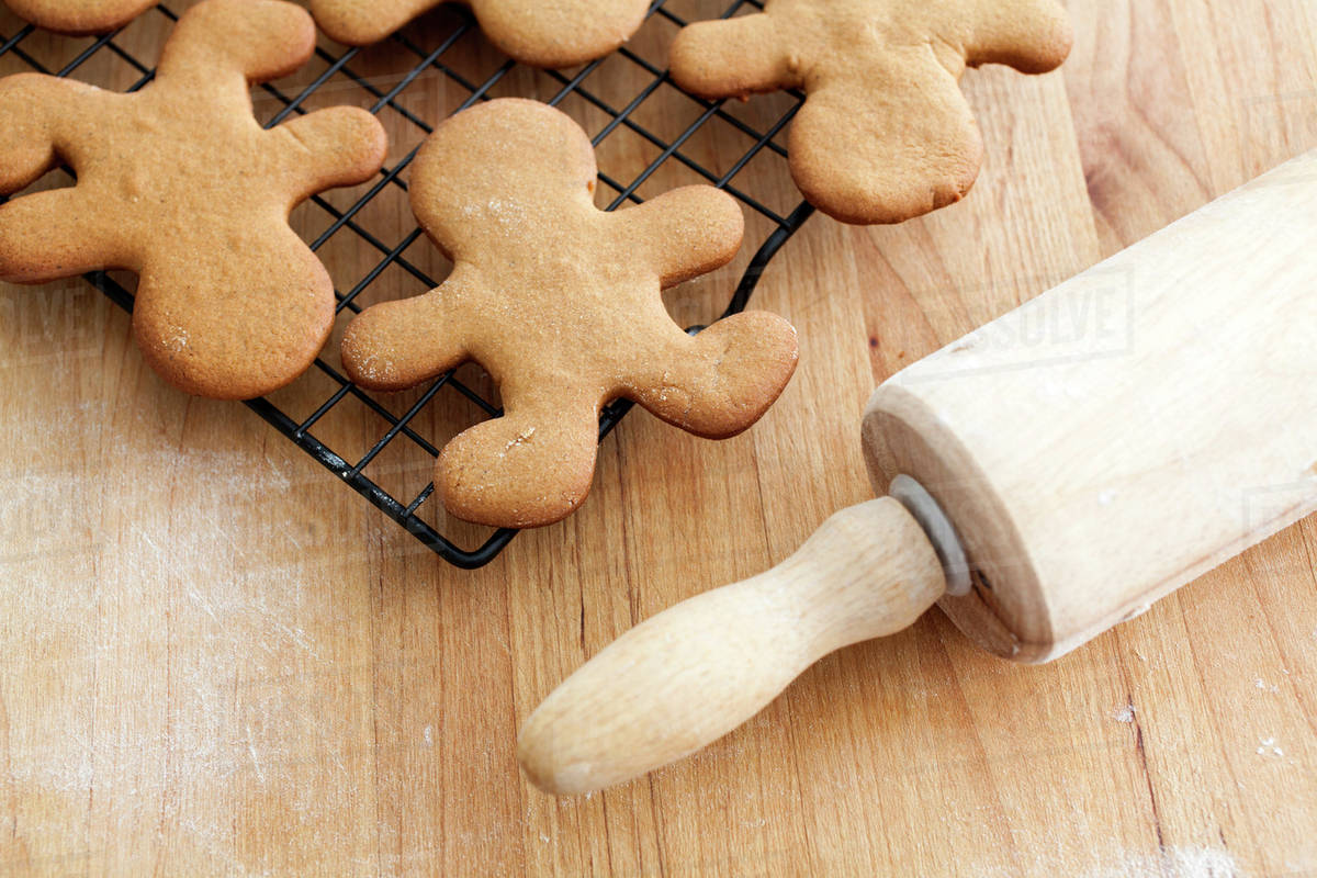 Gingerbread man cookies cooling on a rack next to a rolling pin - Stock ...