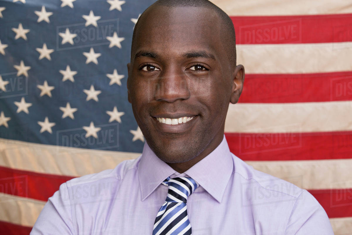 Smiling man in front of American flag - Stock Photo - Dissolve