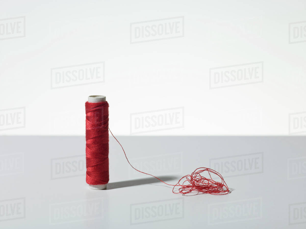 A spool of red thread with a pile of tangled thread - Royalty-free ...